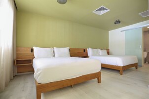 Quarto de hotel com duas camas, cabeceira de madeira, mesa de cabeceira e piso claro.