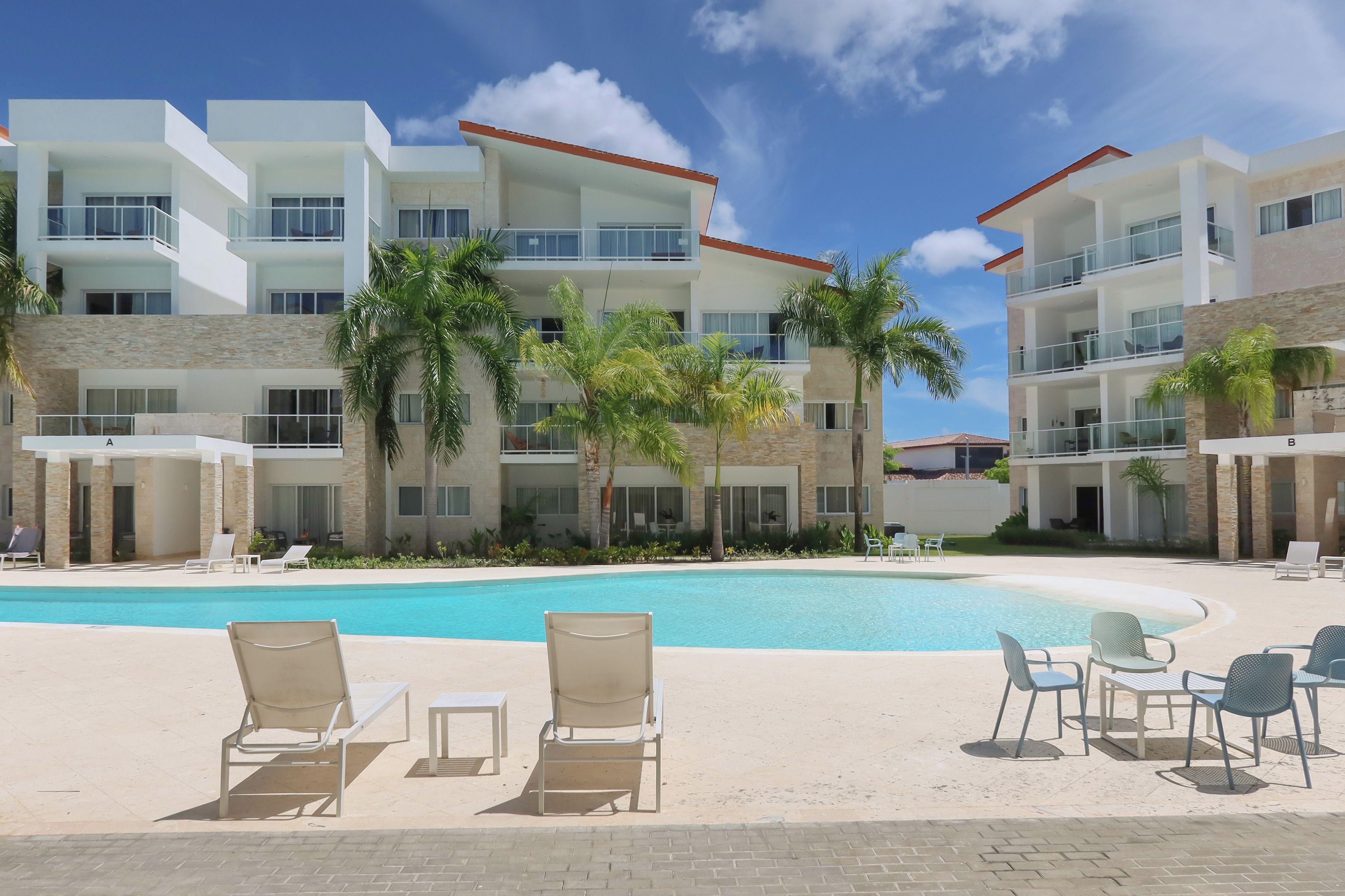 Um resort com piscina, espreguiçadeiras e palmeiras.