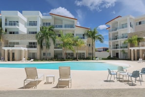 Um resort com piscina, espreguiçadeiras e palmeiras.