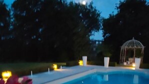 Piscina com gazebo e plantas em vasos.