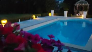Piscina com gazebo e plantas em vasos.