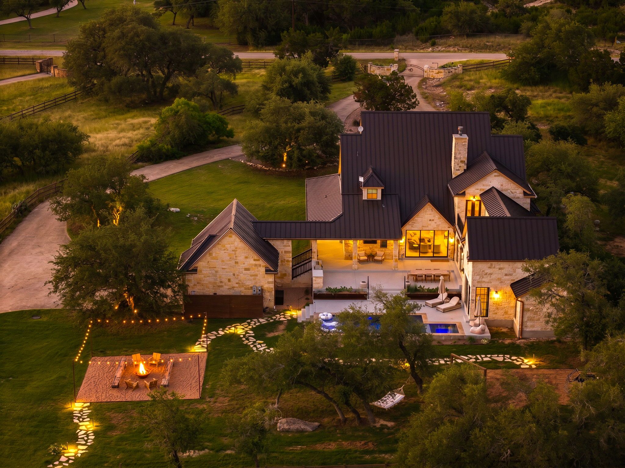 Uma casa grande e com vários andares, fachada de pedra, piscina e gramado bem cuidado.
