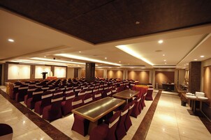 Uma sala de conferências com fileiras de cadeiras, um púlpito e mesas.