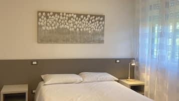 Quarto moderno com cama grande, mesa de cabeceira com abajur e quadro pendurado na parede.