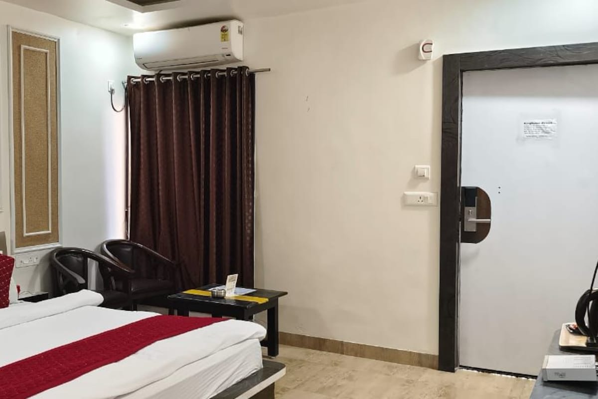 Quarto de hotel com cama, escrivaninha, cadeira, ar-condicionado e porta.