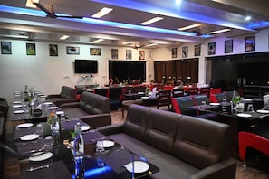 Restaurante com várias áreas de refeições, incluindo cabines e mesas, com ventiladores de teto e iluminação embutida.