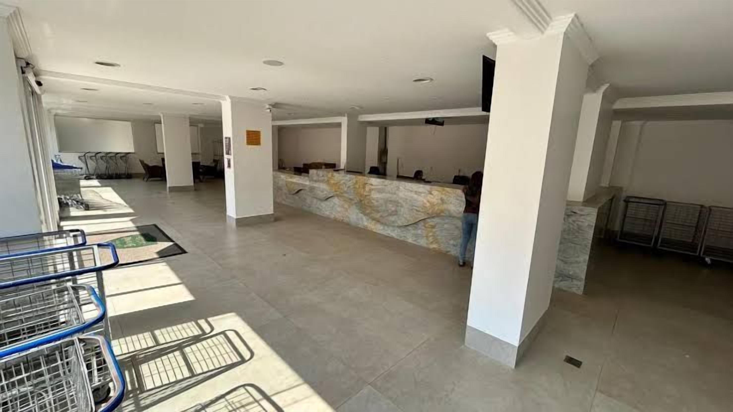Um hall espaçoso com balcão de recepção, área de estar e vista para a área externa.