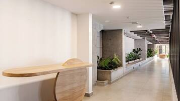 Um interior moderno com um banco de madeira, pilares de concreto e plantas em vasos.