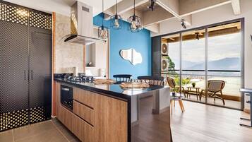 Cozinha moderna com uma ilha grande, parede azul decorativa e vista para o exterior.