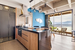 Cozinha moderna com uma ilha grande, parede azul decorativa e vista para o exterior.