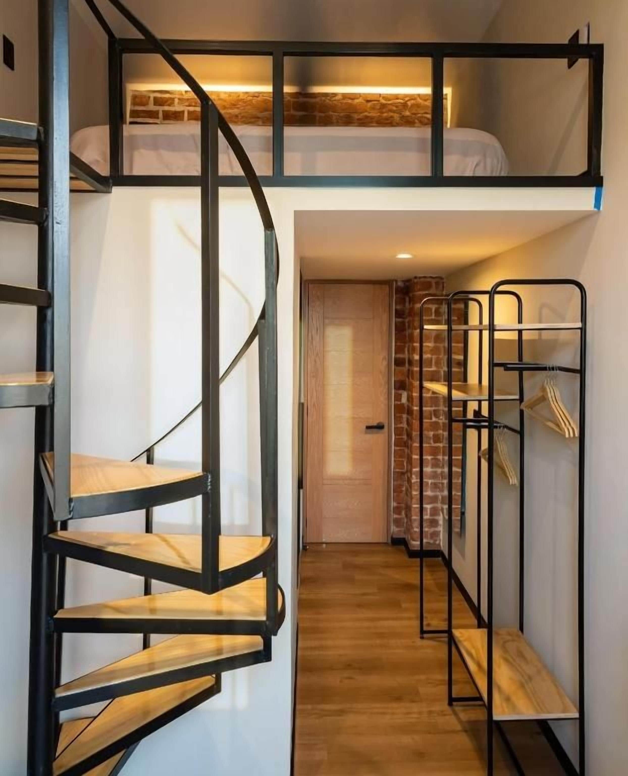 Quarto compacto com beliche, escada em espiral e um banco ao longo da parede.