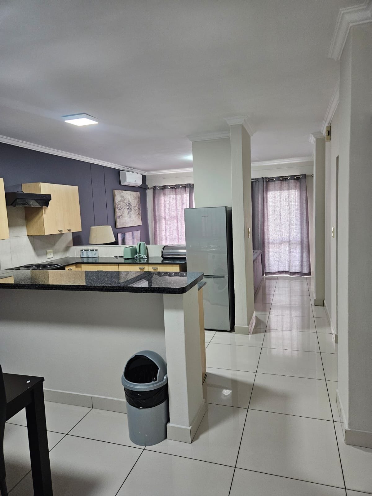 Uma cozinha moderna com ilha central, forno embutido e geladeira.