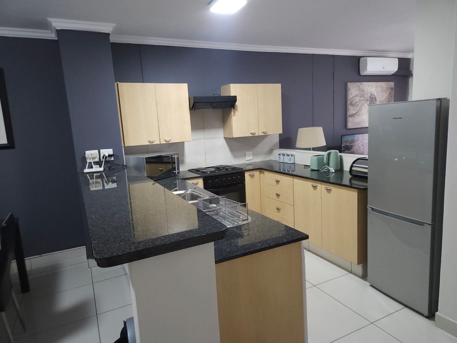 Cozinha compacta com ilha central, fogão, micro-ondas e geladeira.
