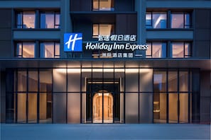 Entrada de um hotel Holiday Inn Express com design moderno, com grandes portas de vidro e sinalização destacada.