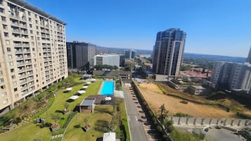 Um edifício residencial alto com piscina, áreas verdes e vista clara da paisagem urbana ao redor.