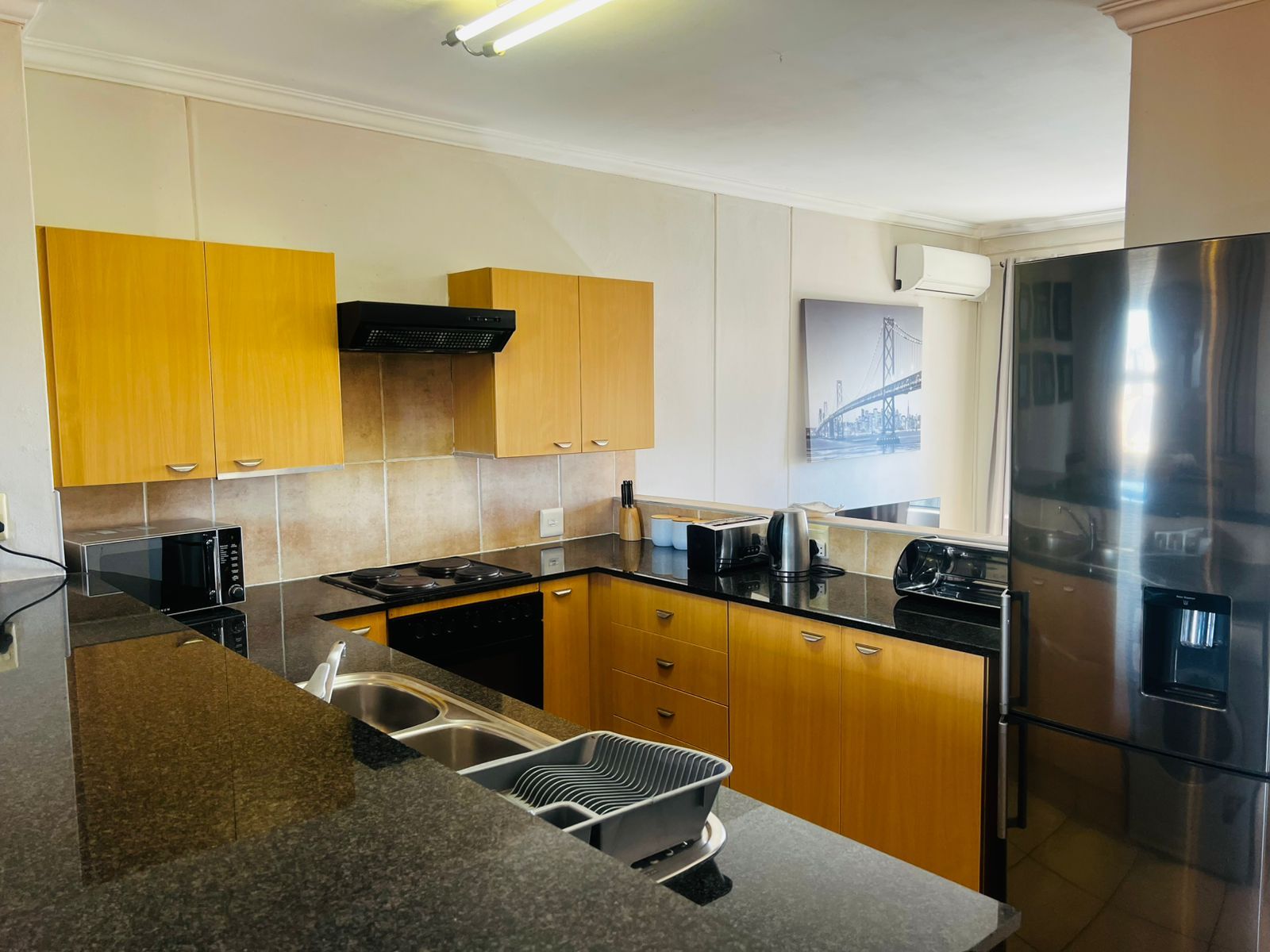 Cozinha moderna com armários de madeira, geladeira de aço inoxidável e micro-ondas.