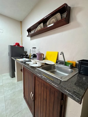 Cozinha com bancada de granito, pia, fogão e prateleira embutida acima da bancada.