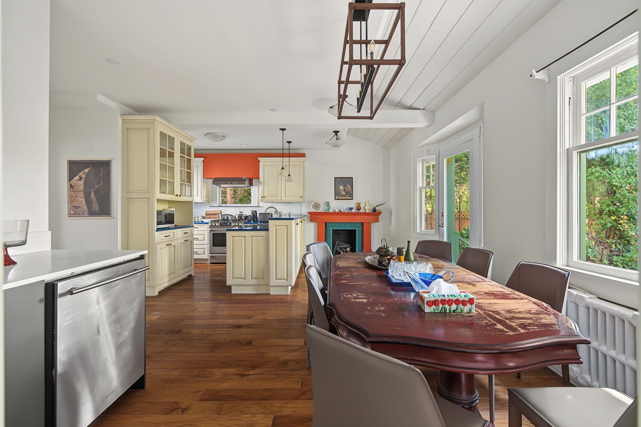 Cozinha espaçosa com piso de madeira, área de jantar com uma mesa grande e vista para o verde lá fora.