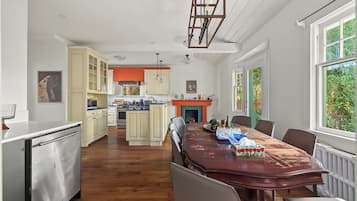 Cozinha espaçosa com piso de madeira, área de jantar com uma mesa grande e vista para o verde lá fora.