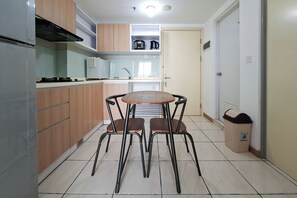 Cozinha compacta com mesa e cadeiras, fogão embutido e lixeira.