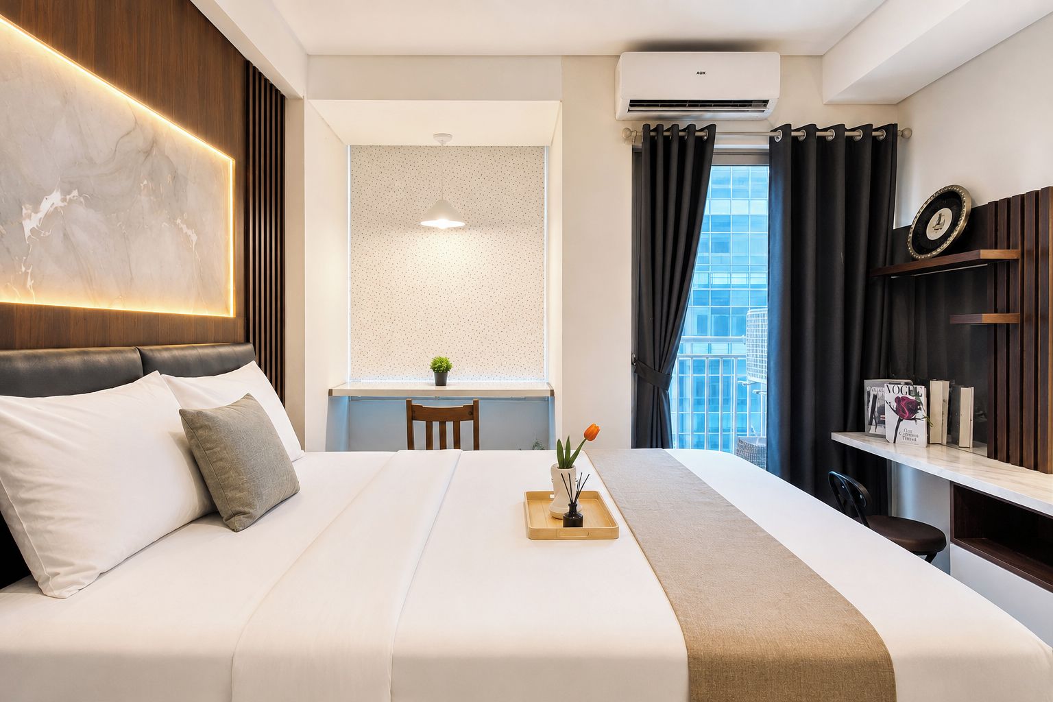 Quarto de hotel com cama, escrivaninha, janela com cortinas e ar condicionado.