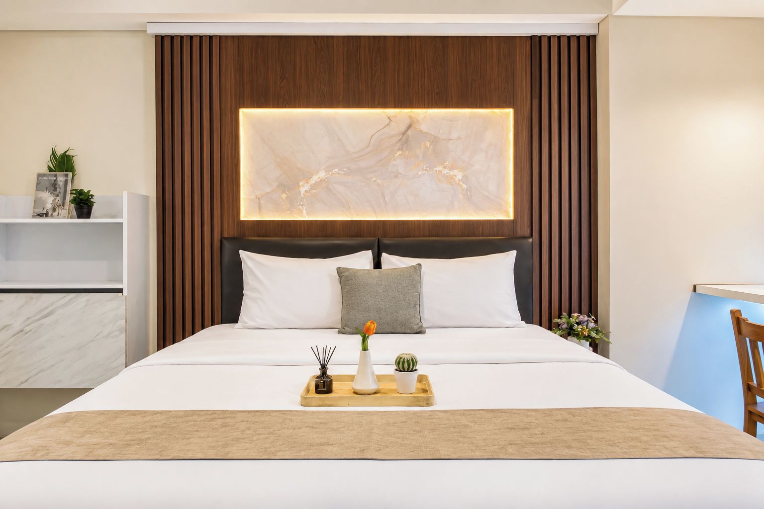Quarto de hotel com uma cama, mesa de cabeceira com bandeja, uma obra de arte na parede e cabeceira de madeira.