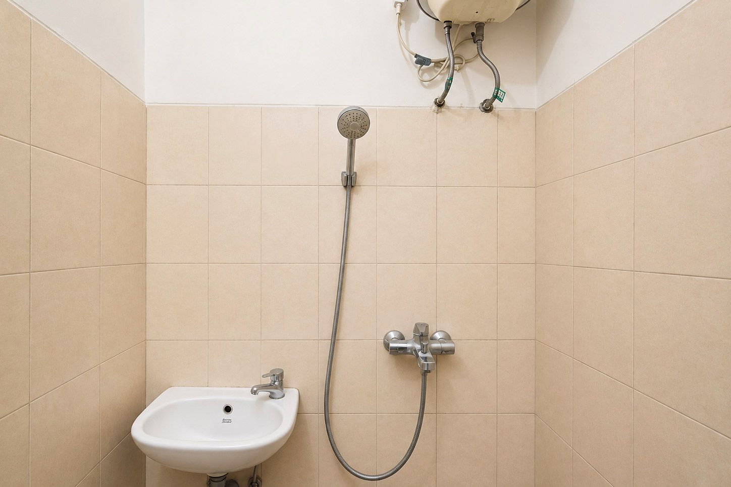 Casa de banho com chuveiro, pia e canalização aparente.