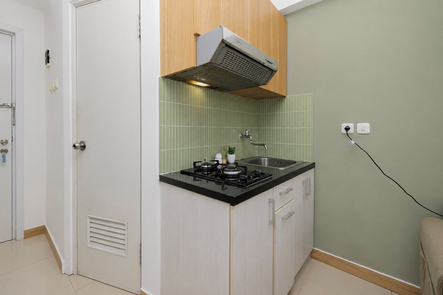 Uma cozinha compacta com fogão a gás, forno embutido, pia e exaustor.