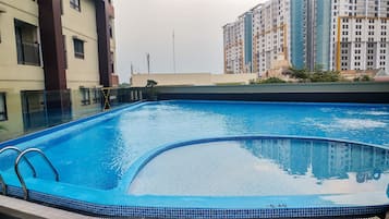 Piscina com borda azulejada, cercada por edifícios altos.