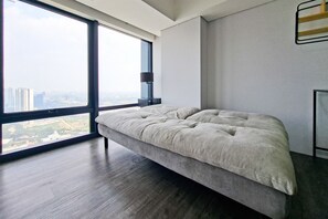 Quarto moderno com janela grande, cama e mesa de cabeceira.