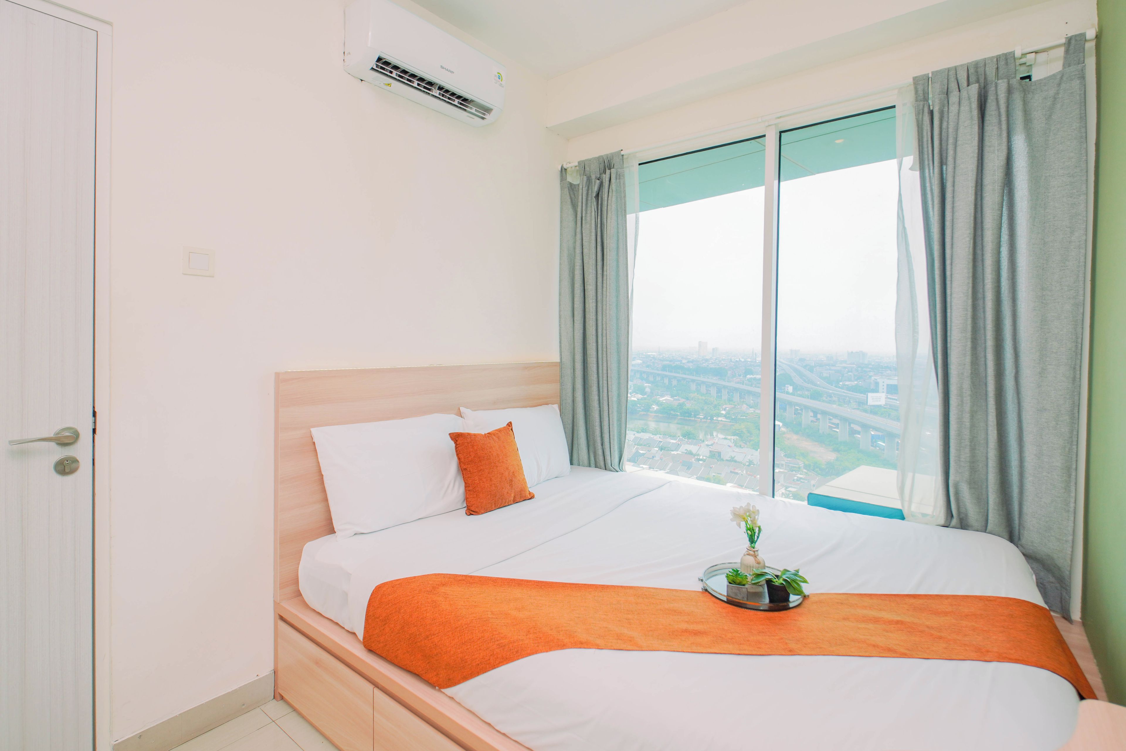 Quarto de hotel com cama, janela com cortinas, vista para a paisagem urbana e ar condicionado.