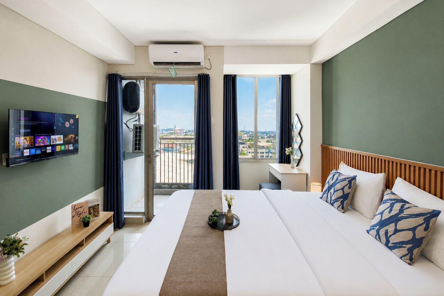 Quarto de hotel com cama, televisão na parede, janela com cortinas e varanda com vista.