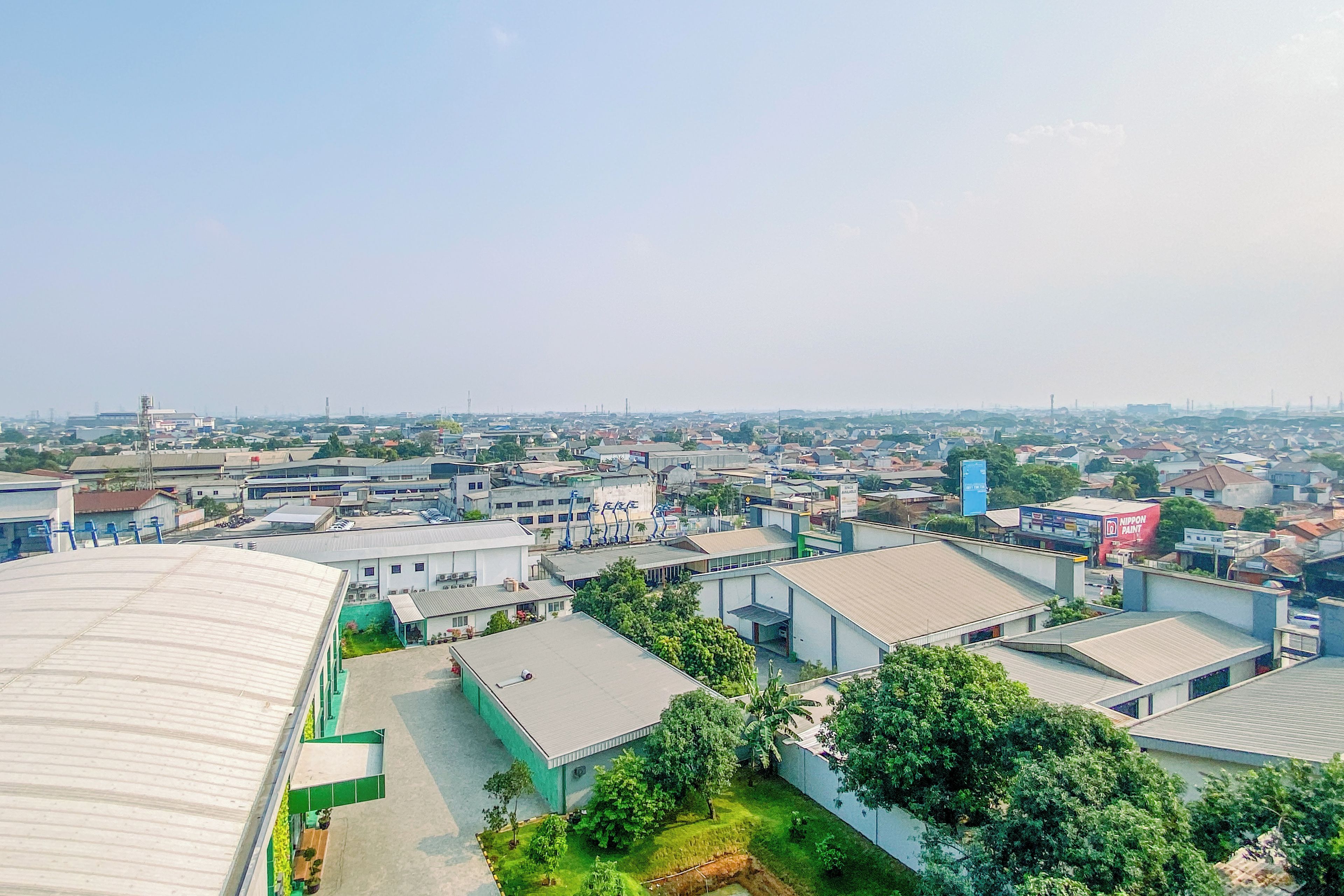 Grande área industrial com vários armazéns e edifícios, cercada por vegetação.