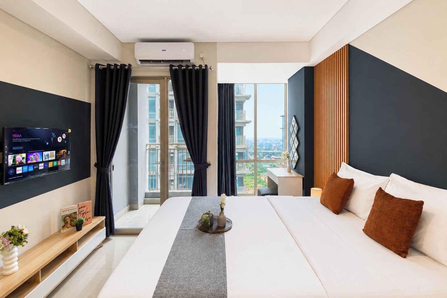 Quarto de hotel com cama grande, televisão na parede, varanda com cortinas e vista para a cidade.