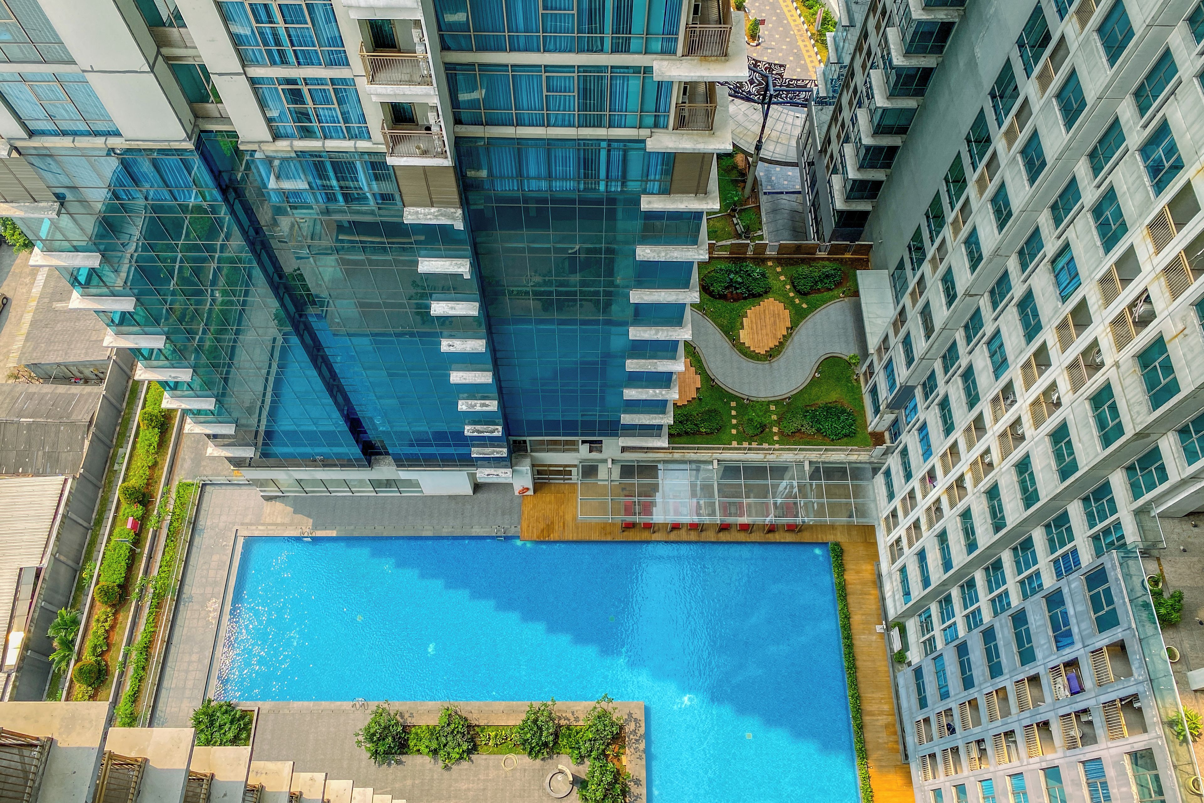 Um edifício alto com piscina e vegetação ao redor.