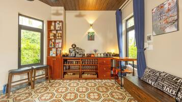 Quarto aconchegante com espaço para café, prateleiras com bolsas, piso estampado e vista pela janela.