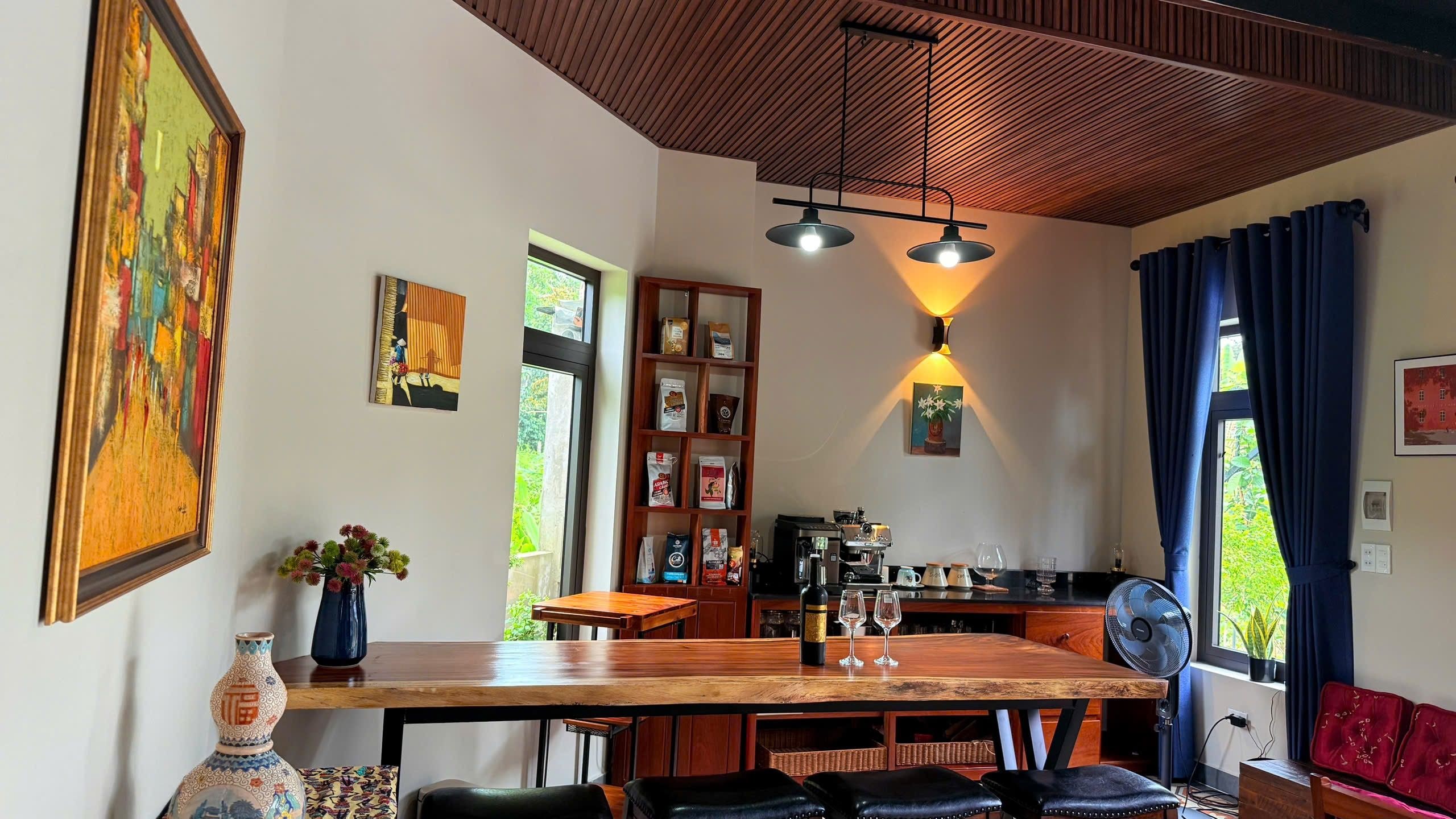 Uma cozinha aconchegante com uma mesa de madeira, uma cafeteira e um ventilador.