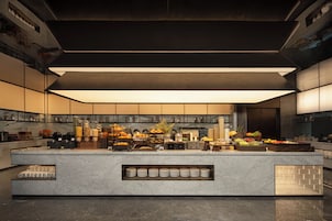 Cozinha moderna com bancada de mármore, diversos alimentos e uma luminária grande.