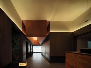 Um interior moderno com um corredor comprido, painéis de madeira e um balcão de recepção.