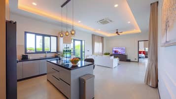 Um espaço de estar moderno com cozinha, área de refeições e televisão na sala.