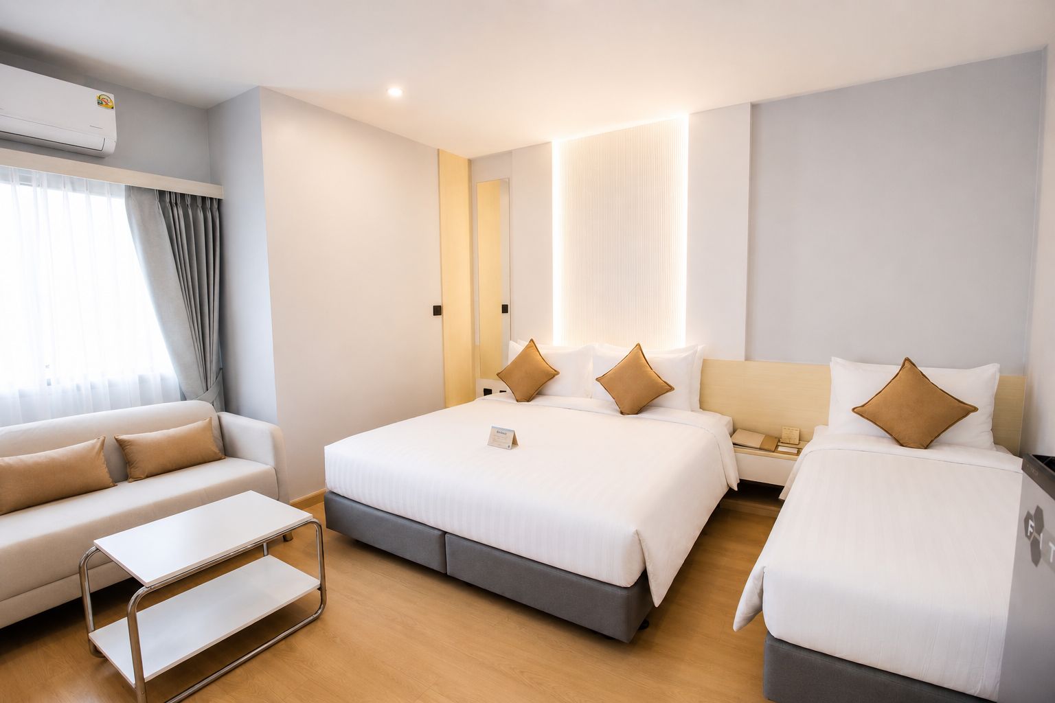Quarto de hotel com uma cama, um sofá, uma mesinha e uma mesa de cabeceira.