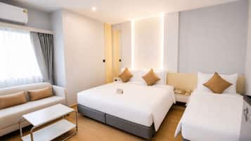 Quarto de hotel com uma cama, um sofá, uma mesinha e uma mesa de cabeceira.