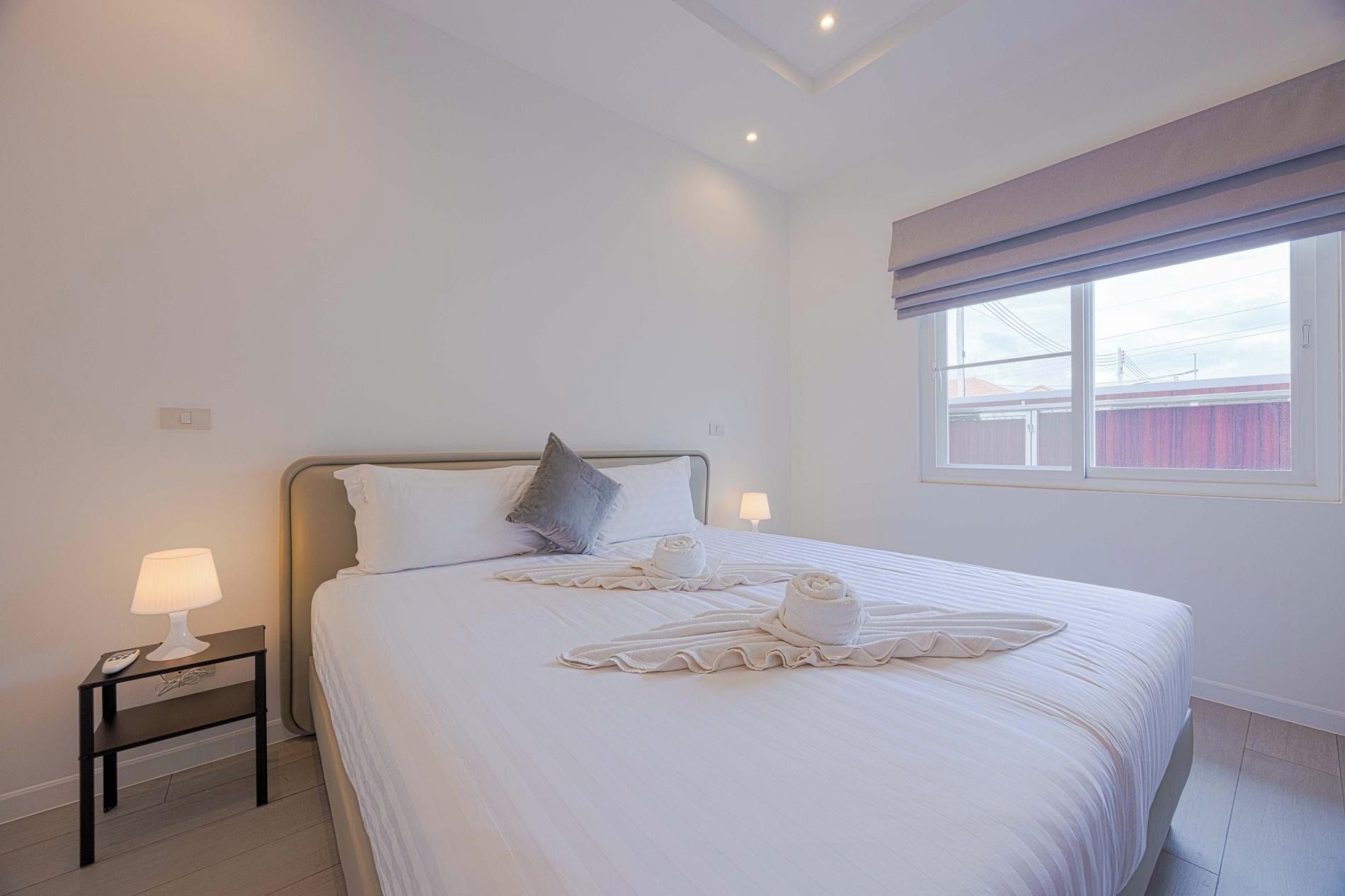 Cama bem arrumada com toalhas, abajur e janela com vista.