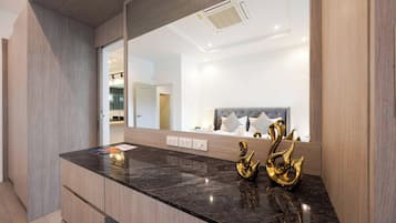 Casa de banho moderna com um espelho grande, bancada de mármore e um objeto decorativo dourado.