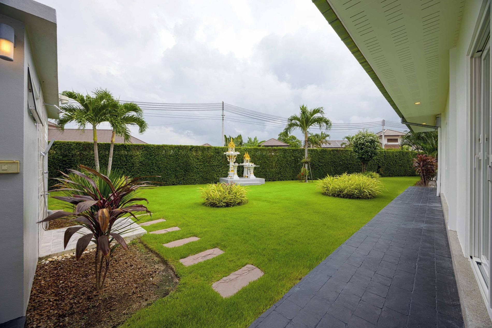 Um jardim bem cuidado com um caminho que leva a uma estrutura branca com detalhes dourados.