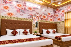 Quarto de hotel com duas camas, cada uma com cabeceira estofada, roupa de cama branca e cobre de cama com padrão em vermelho e dourado.