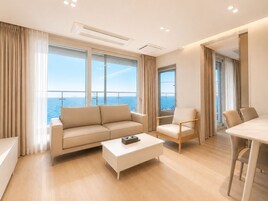 Uma sala de estar moderna com sofá, poltronas, mesa de centro e área de jantar.