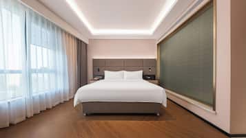 Quarto de hotel moderno com uma cama grande, uma mesa de cabeceira e uma janela ampla com cortinas.