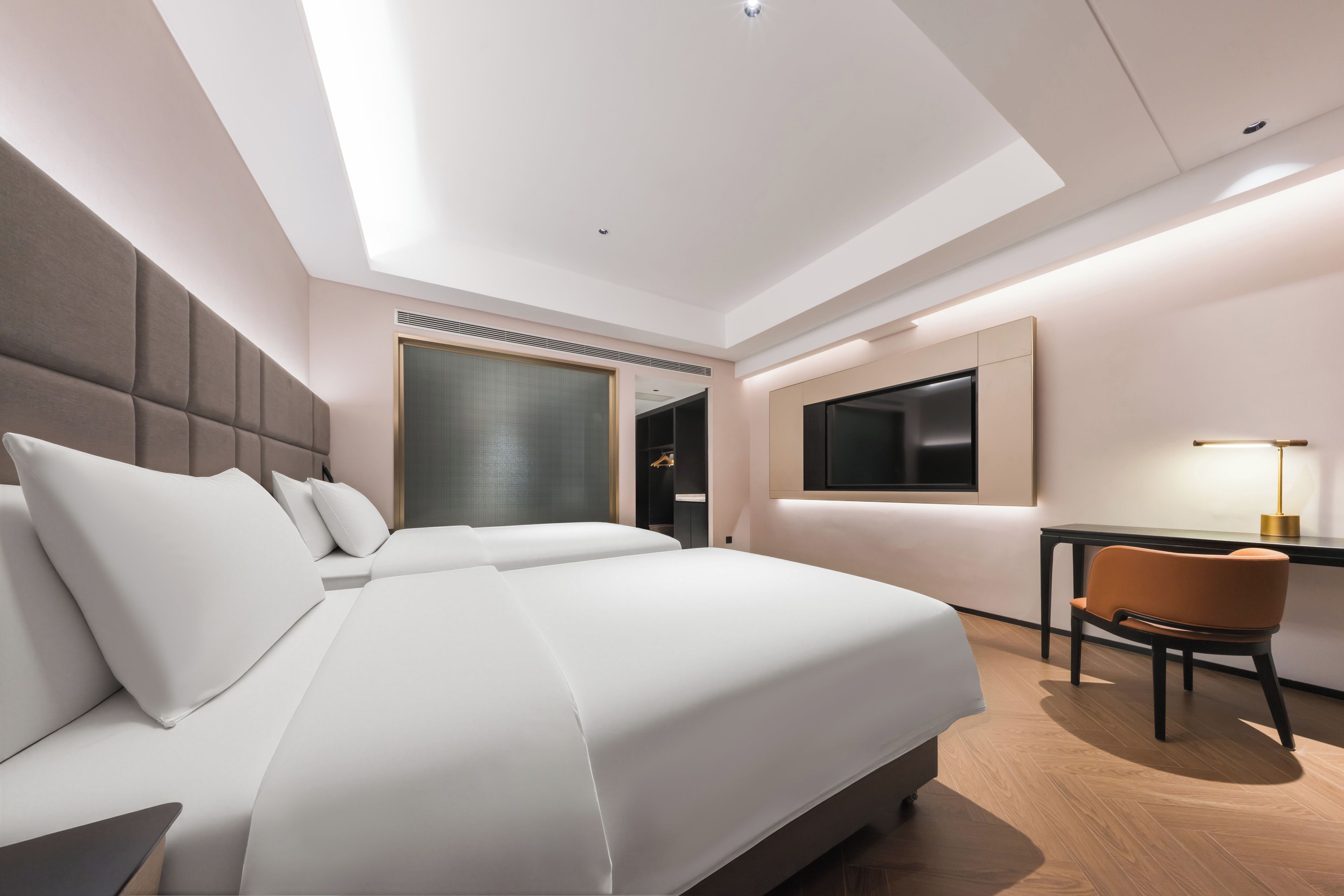 Quarto de hotel moderno com uma cama grande, uma escrivaninha e uma cadeira.