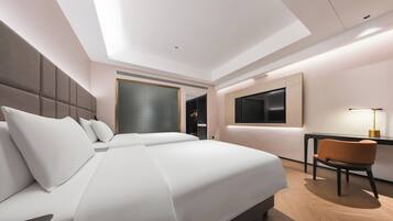 Quarto de hotel moderno com uma cama grande, uma escrivaninha e uma cadeira.